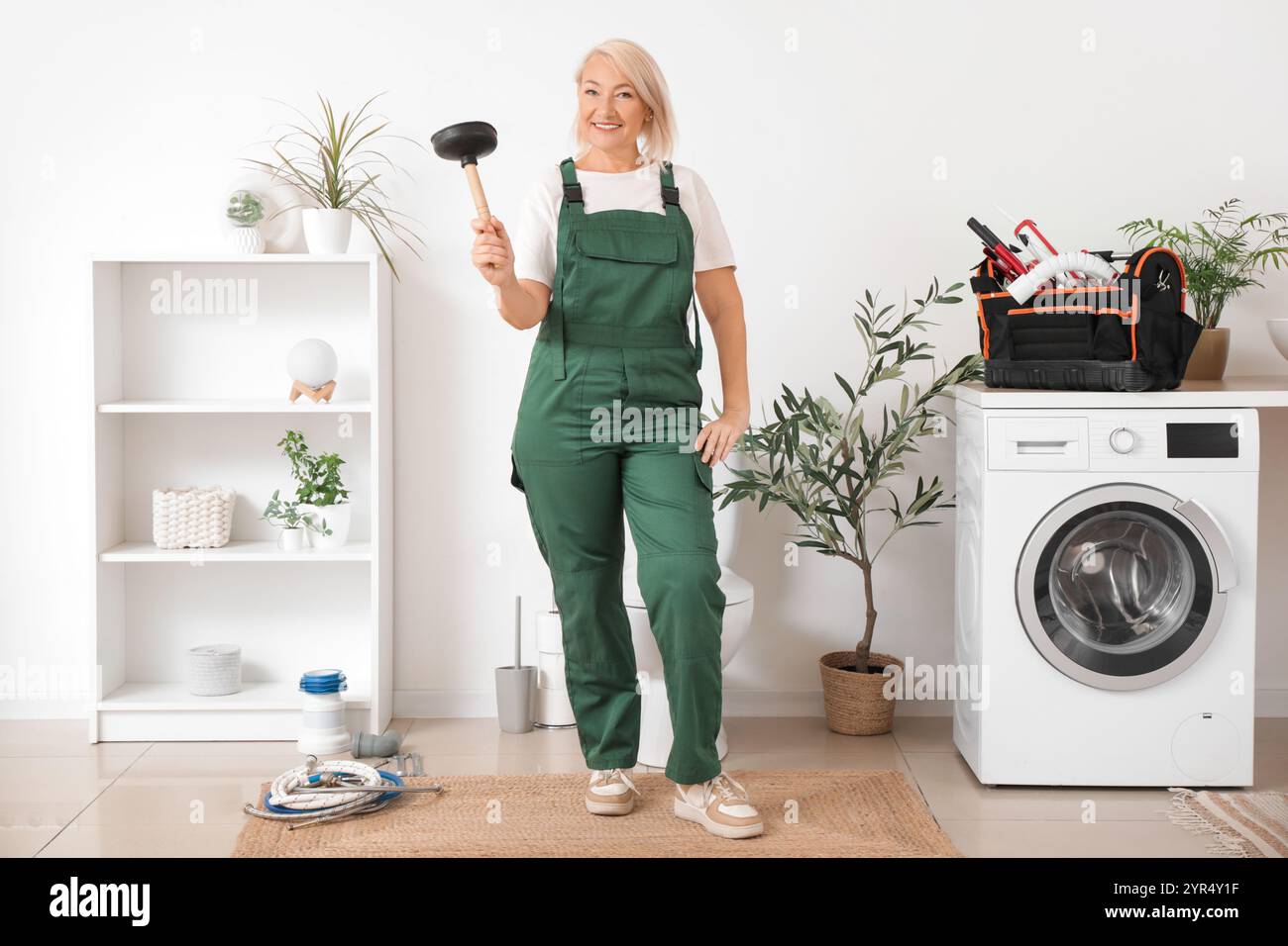 Mature female plumber with plunger in bathroom Stock Photo - Alamy