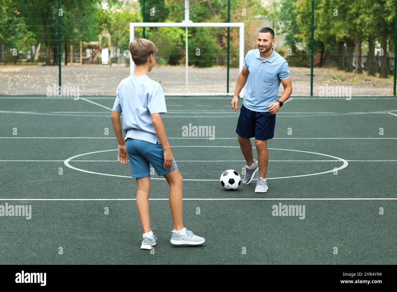 Boy with his dad playing football on field Stock Photo - Alamy