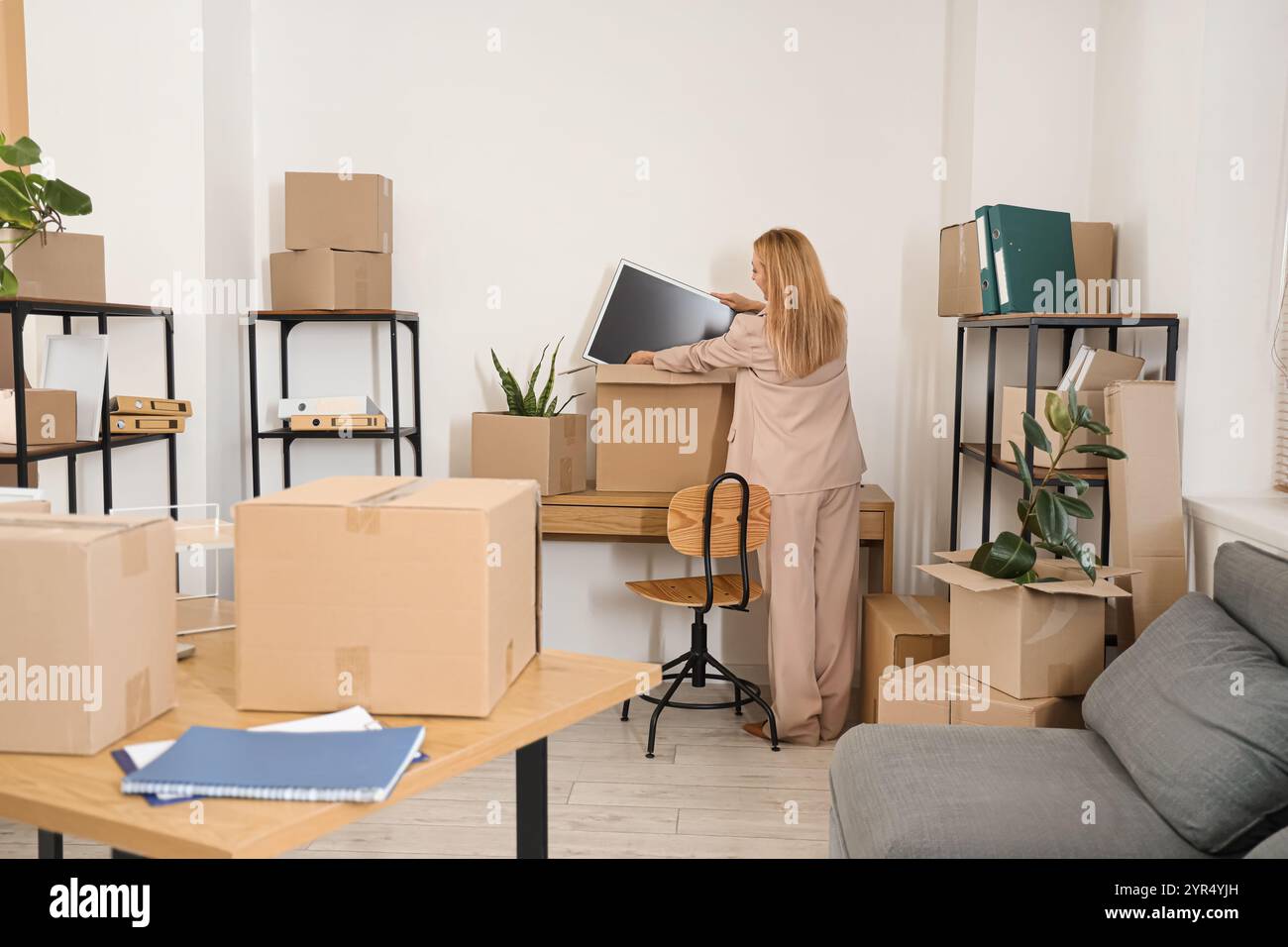Mature businesswoman packing computer monitor into box in office on ...
