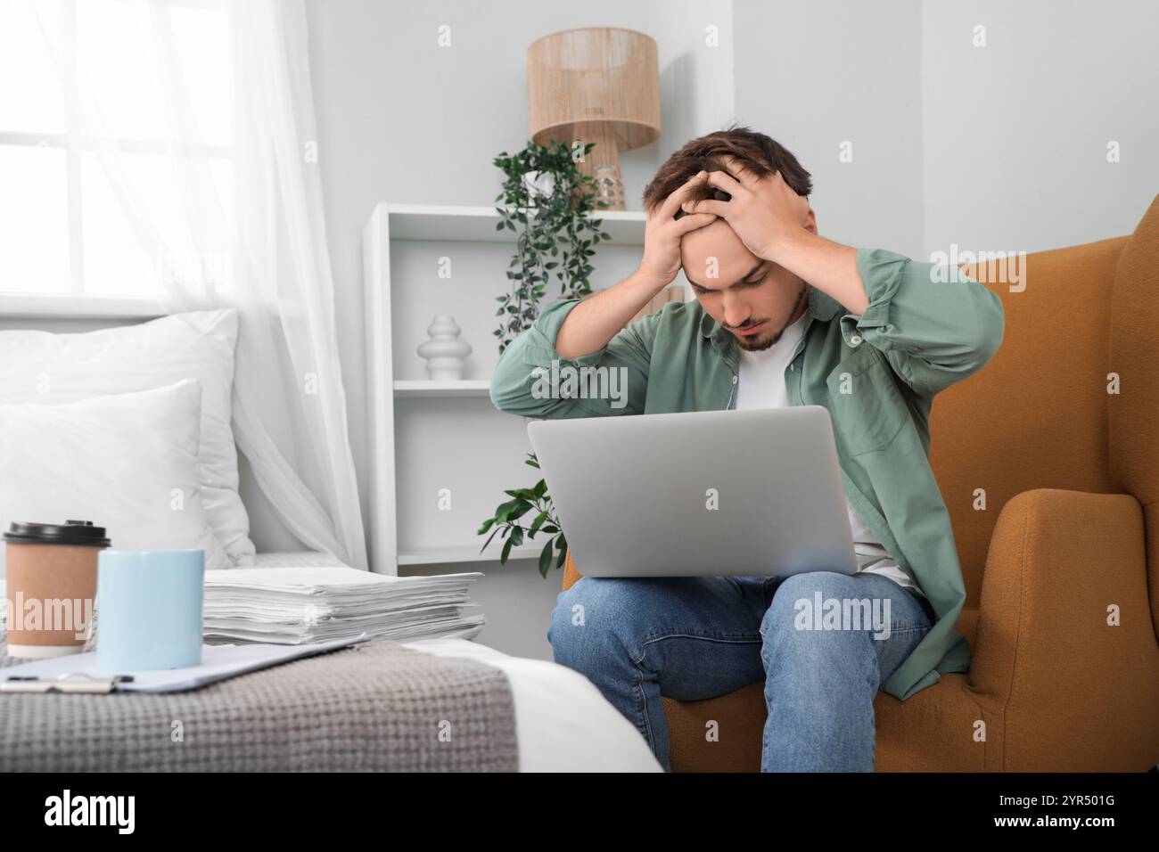 Stressed young man working with laptop in bedroom Stock Photo - Alamy