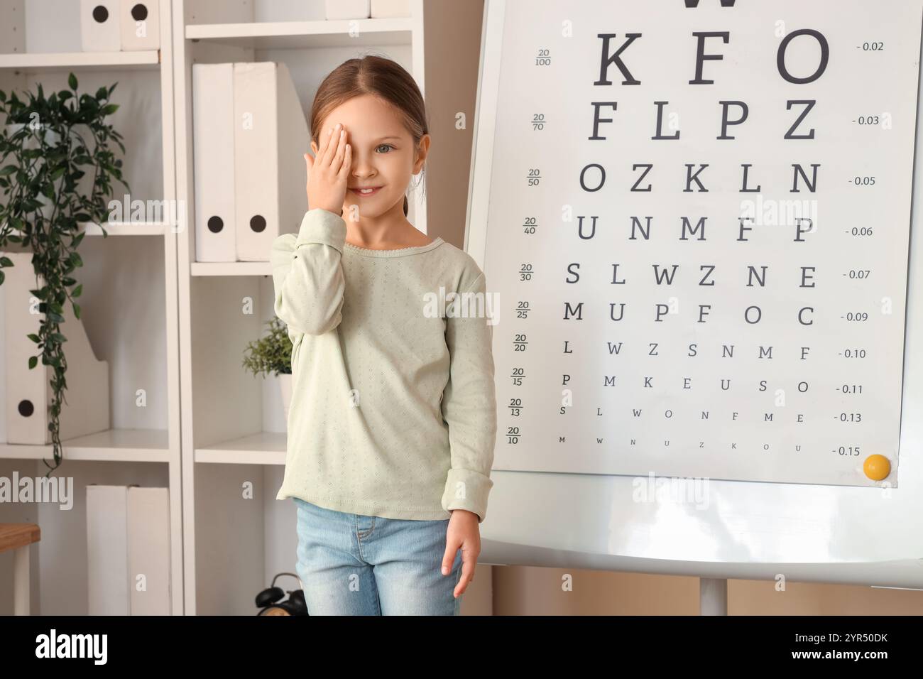 Cute little girl near eye test chart in clinic Stock Photo - Alamy