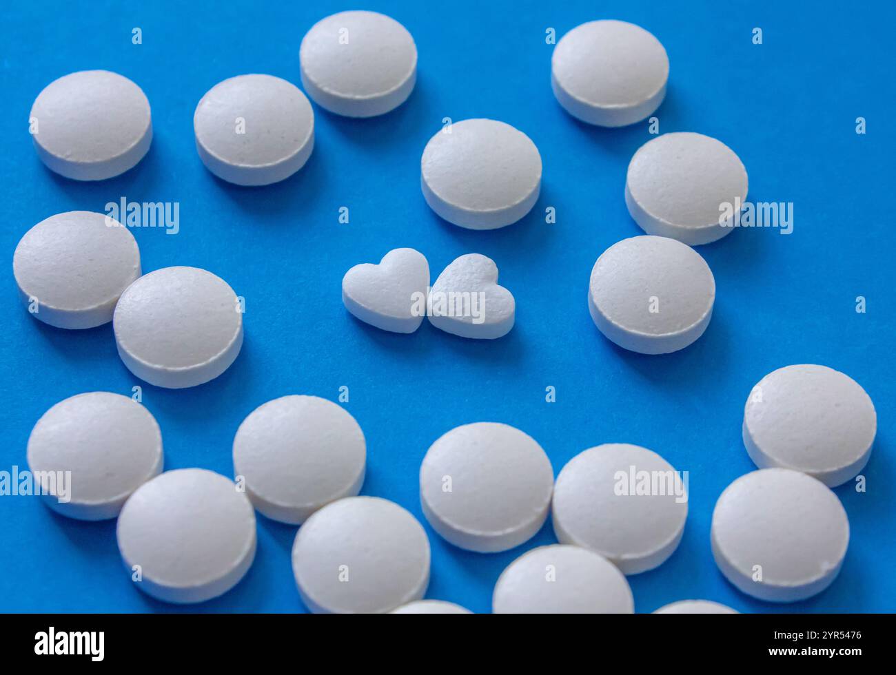 Heart shaped and round white pills on blue background. Global ...