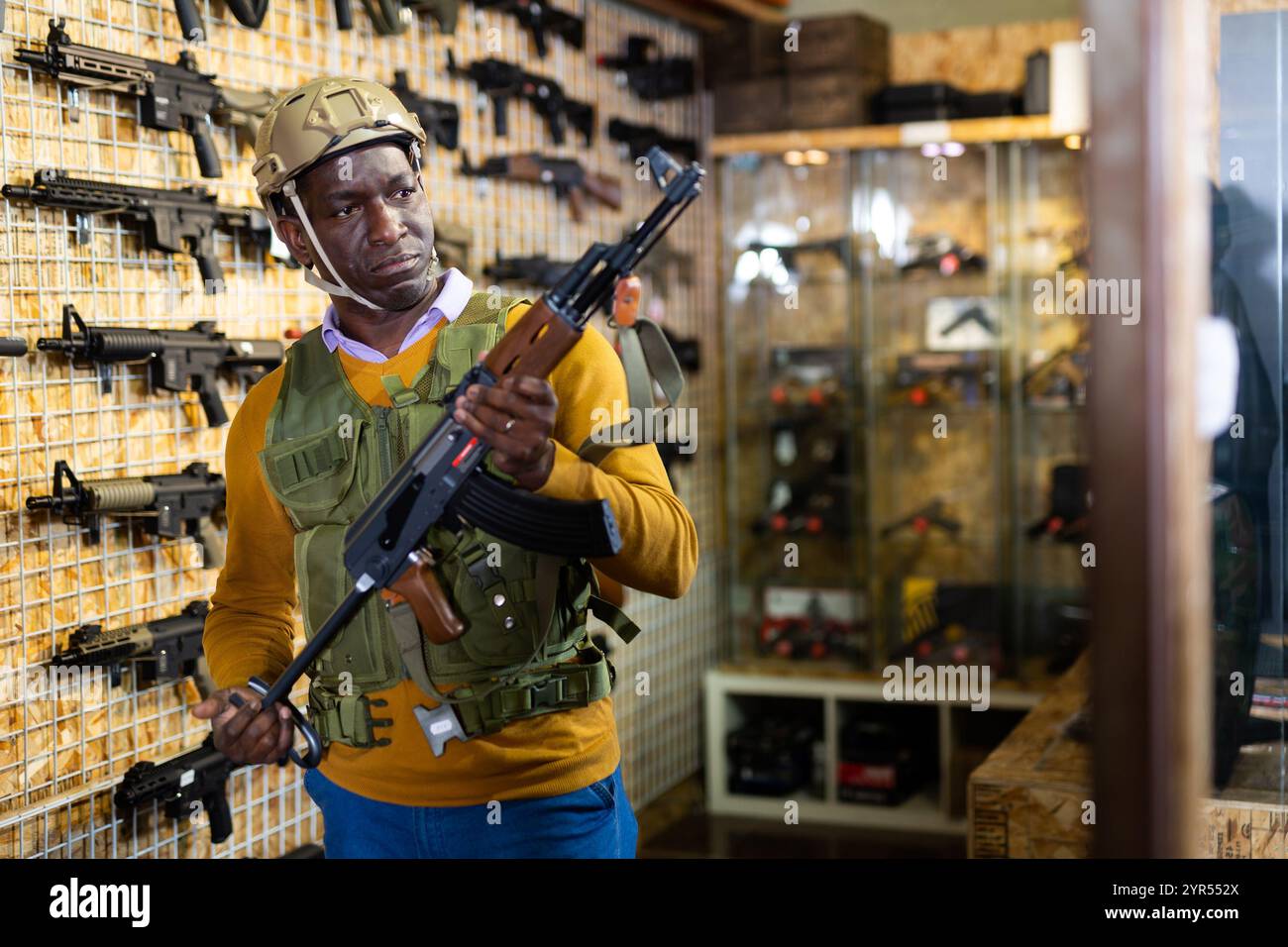 Man in armor vest selecting machine gun in weapon shop Stock Photo - Alamy