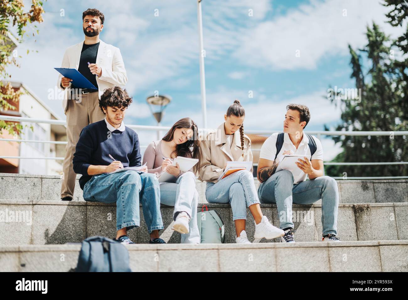 High school students studying outdoors with helpful professor guidance ...