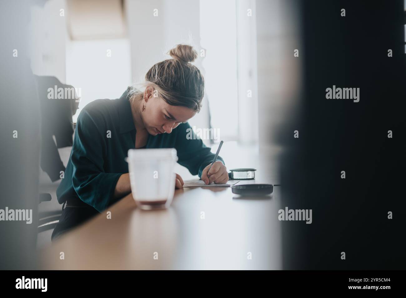 Focused woman writing notes in a modern office setting Stock Photo - Alamy