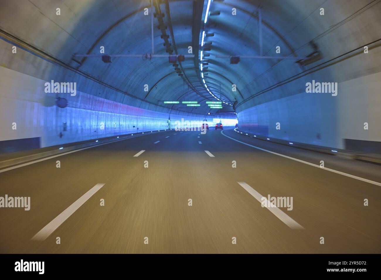 Modern, well-lit motorway tunnel with blue illuminated walls and a ...