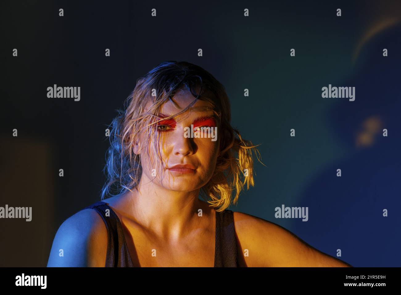 Woman with red eye shadow looks intensely into the camera, enveloped by ...