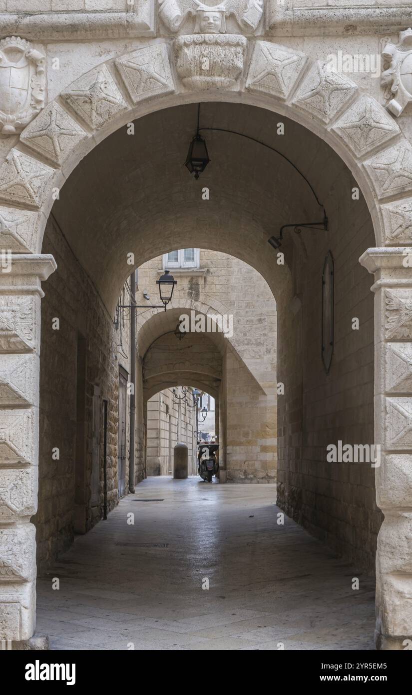 Stone arch above a narrow cobbled alley with antique lamps and historic ...