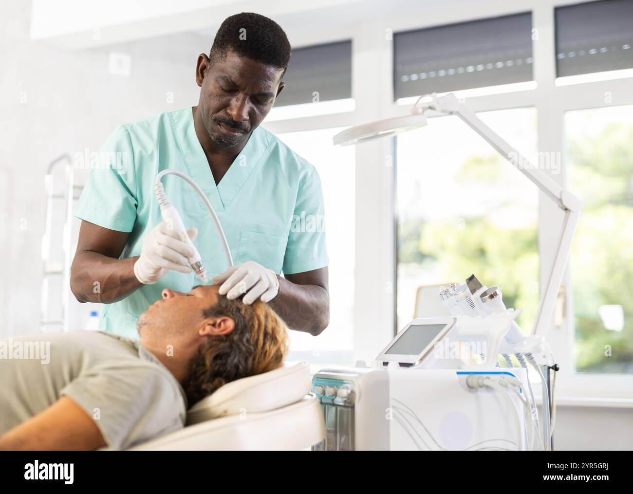 African American esthetician performing facial procedure with ion ...