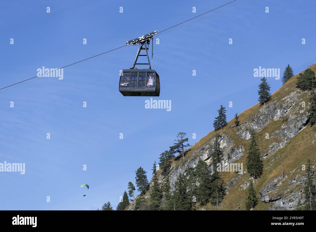 Floating cable car cabin above steep mountain landscape with pine trees ...