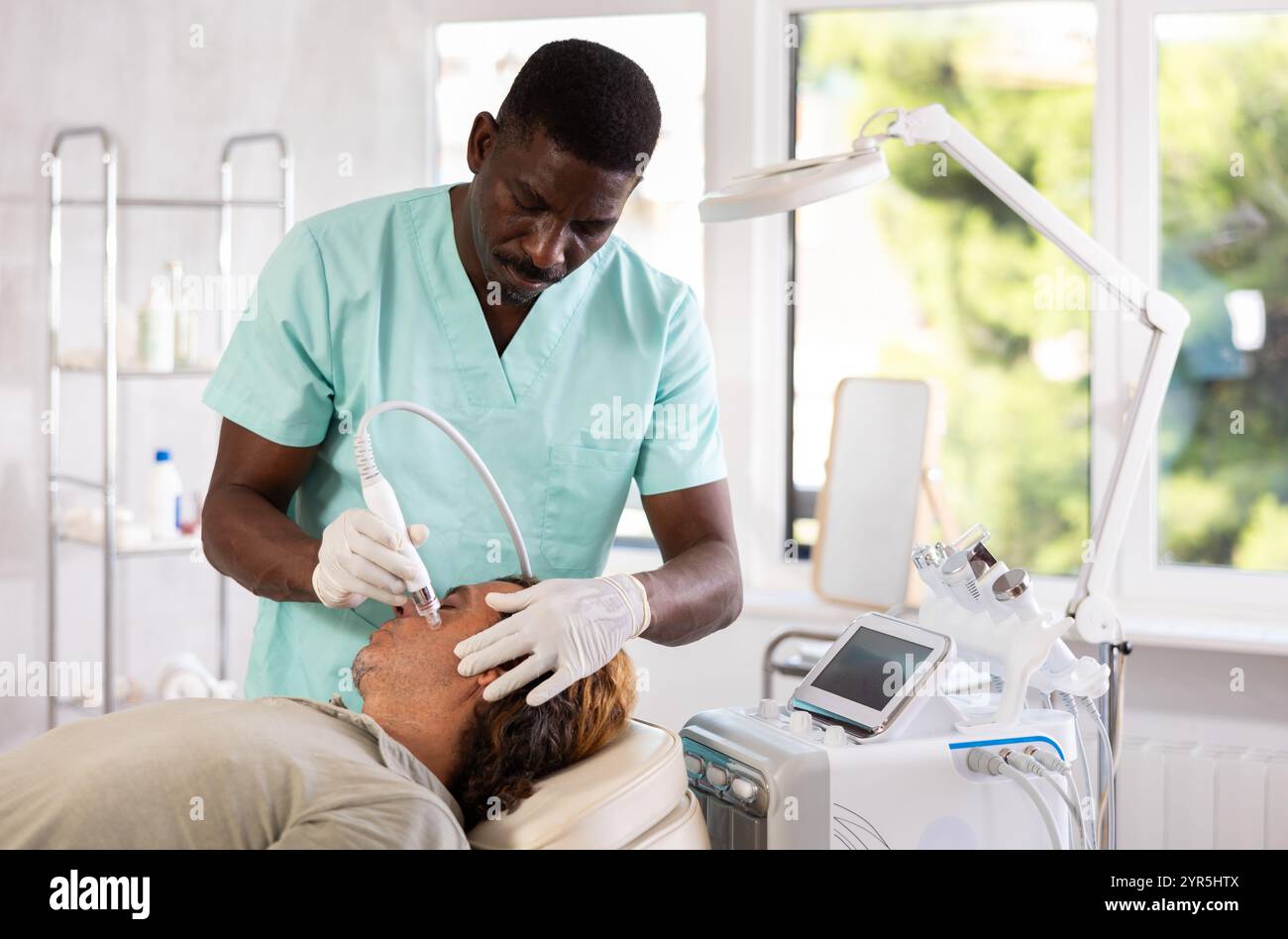 African American esthetician performing facial procedure with ion ...