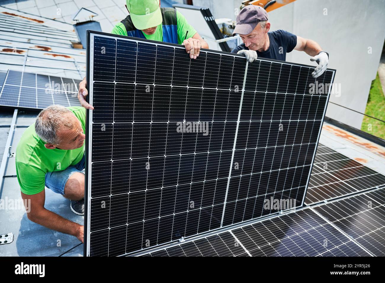 Workers building solar panel system on metal rooftop of house. Three ...