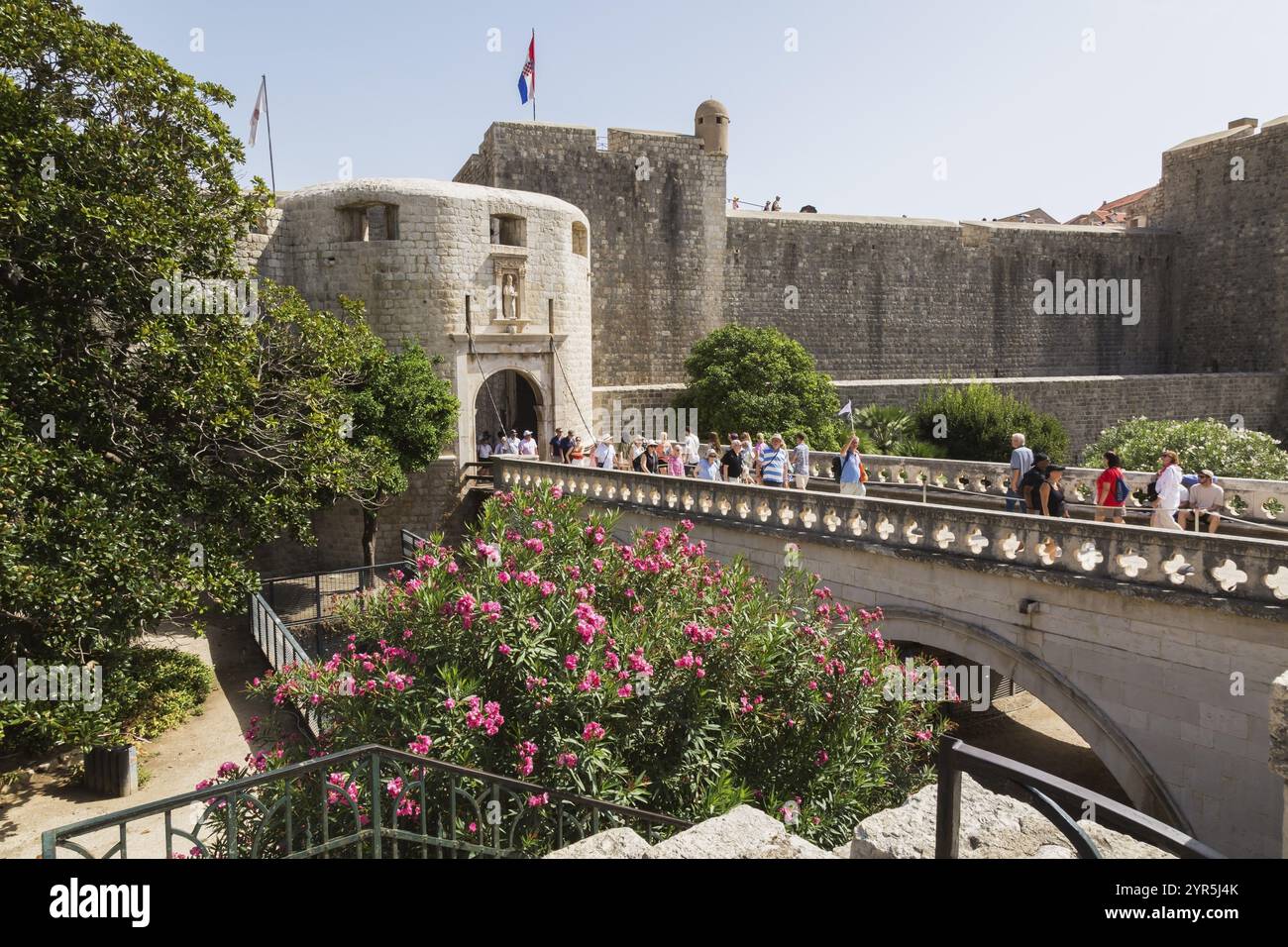 Woman tour guide leading group of tourists across Pile gate bridge from ...