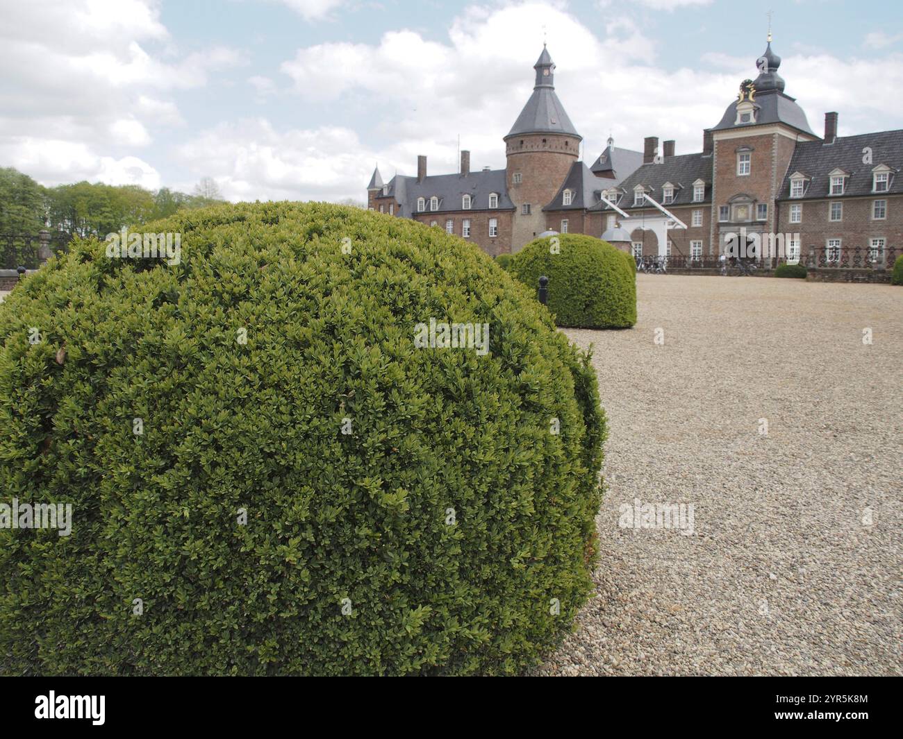 Historic castle with towers and manicured box hedges, surrounded by a ...