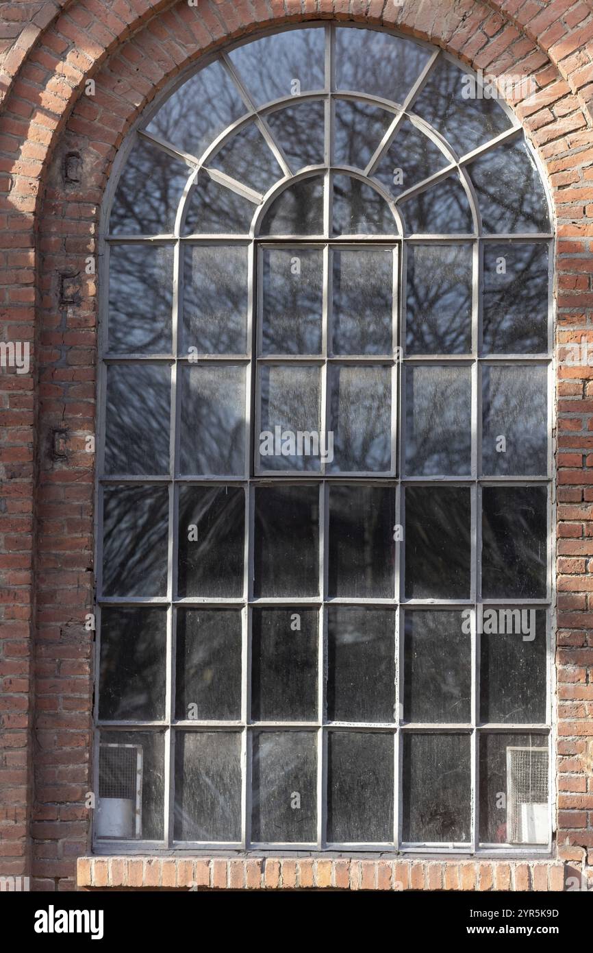Arched window in a brick wall reflecting trees in the sunlight Stock ...