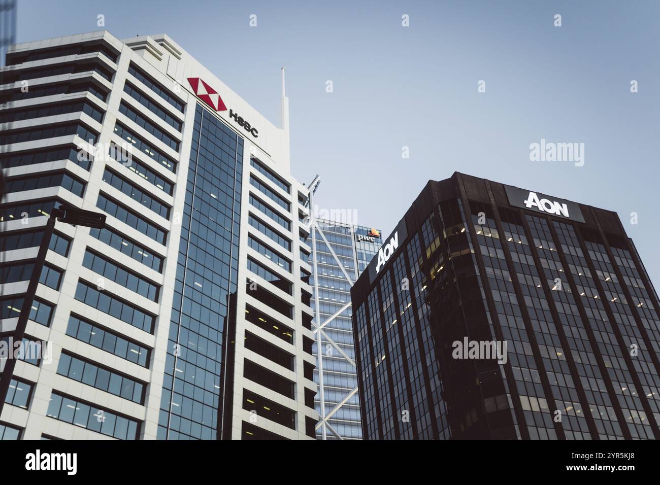 Two modern office buildings with the logos of HSBC, PWC and AON under a ...