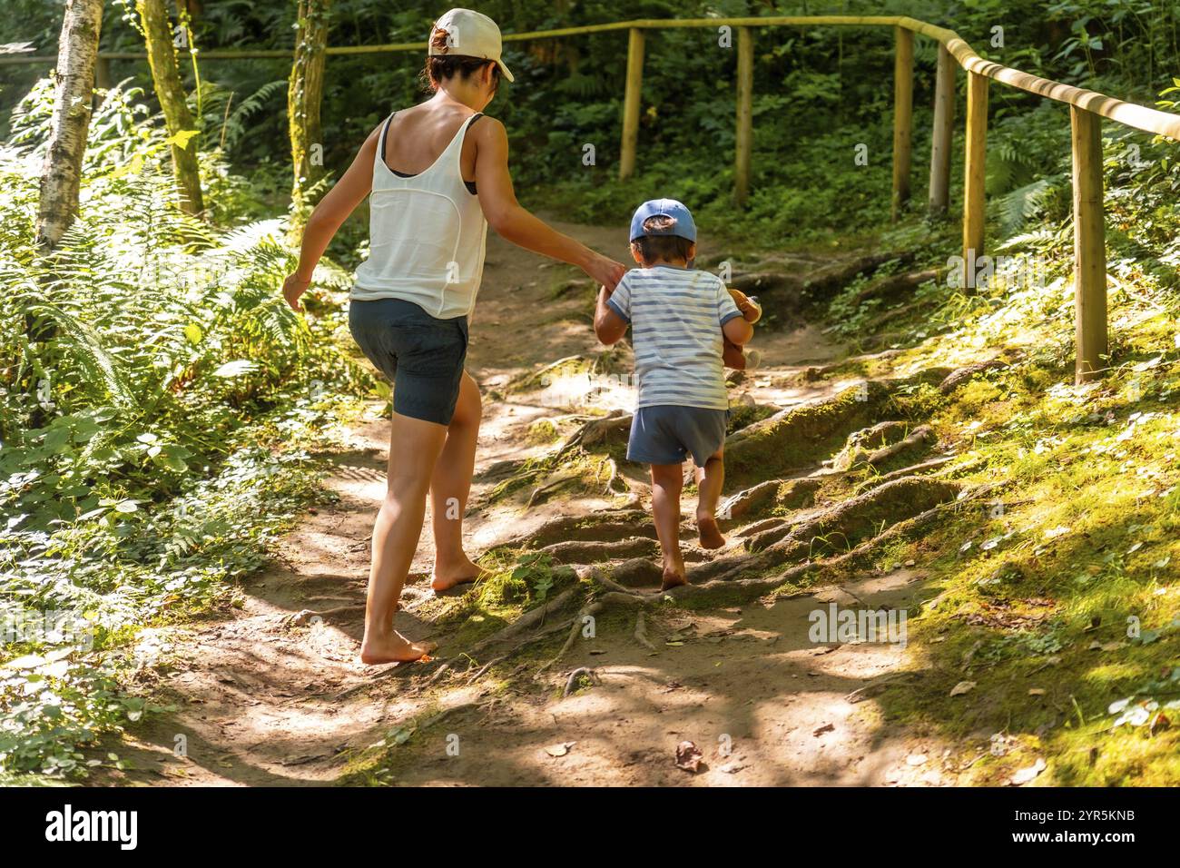 Barefoot mother and son walking in a sensory park to enjoy nature and ...