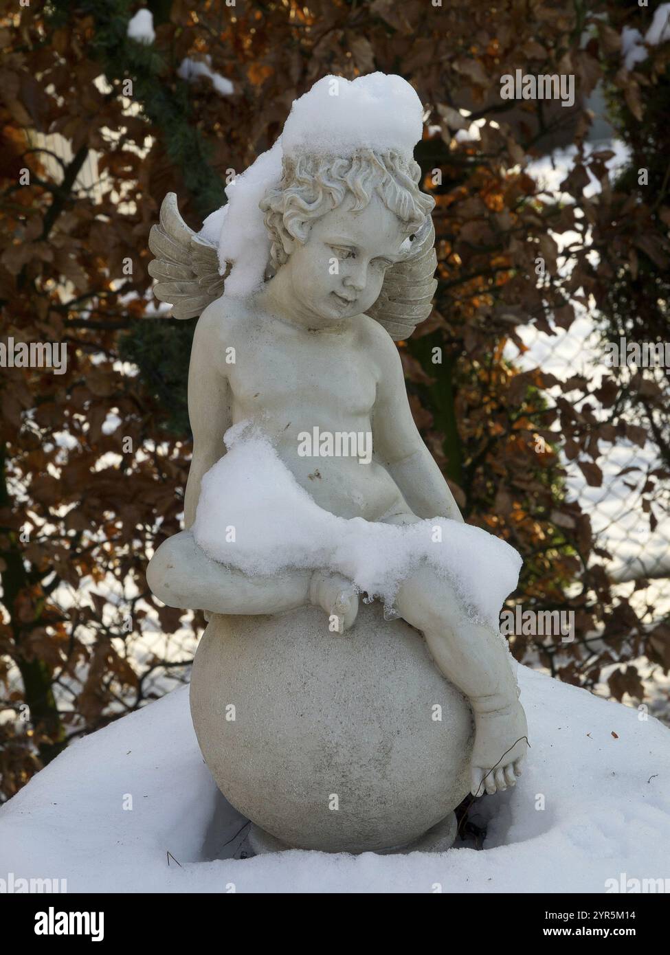 Marble angel with snow covering, embedded in a natural winter scenery ...