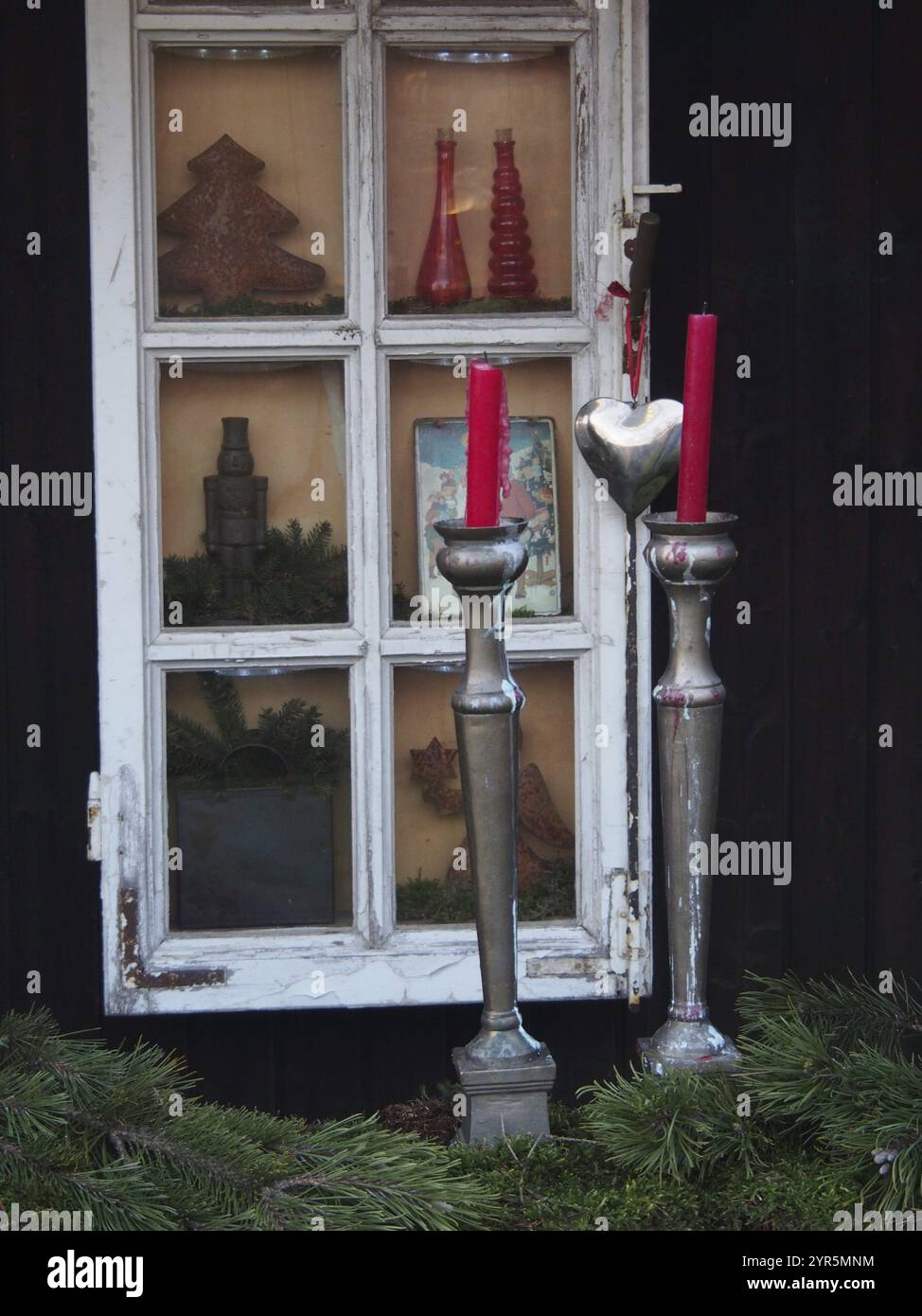 An old window with red candles and Christmas decorations in front of it ...