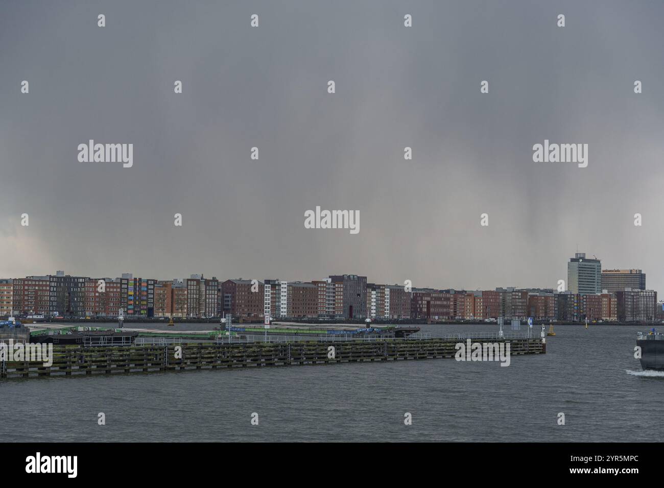 Dramatic cloudy sky over a city skyline on the waterfront with harbour ...