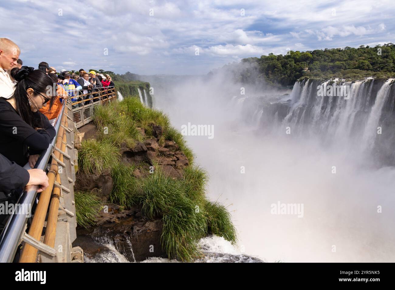Iguazu falls tourism; tourists looking at the waterfall from a walkway ...