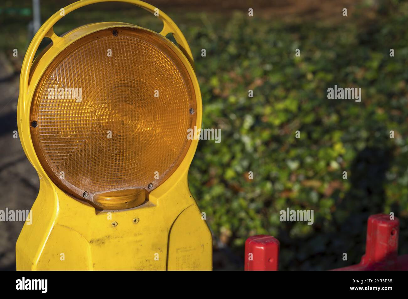 Round orange warning light on yellow plastic support indicating road ...