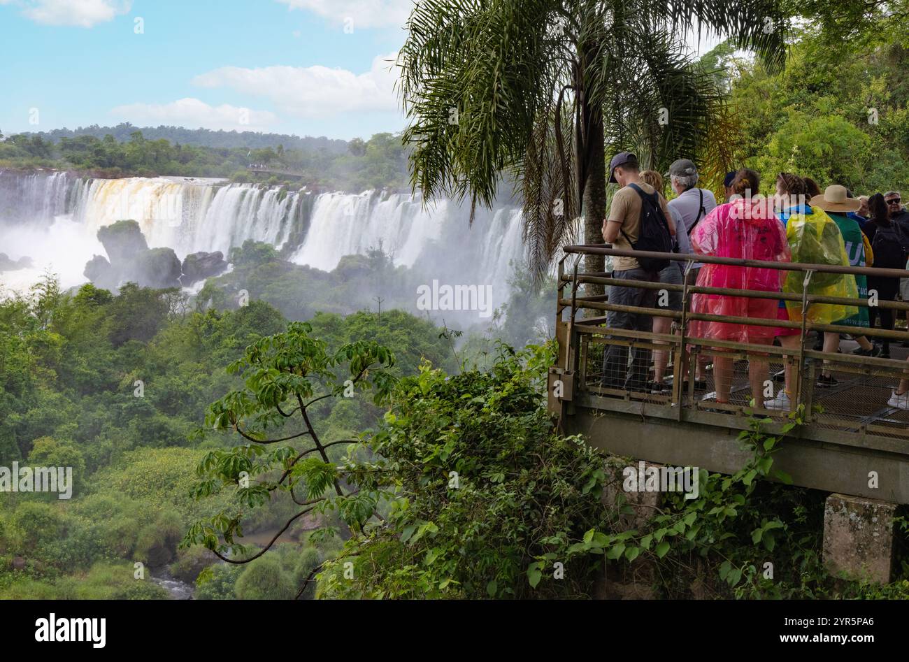 Iguazu falls tourism; tourists looking at the waterfalls from a walkway ...