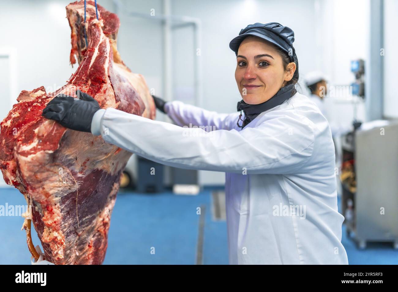 Happy female worker smiling at camera while transporting pieces of meat ...