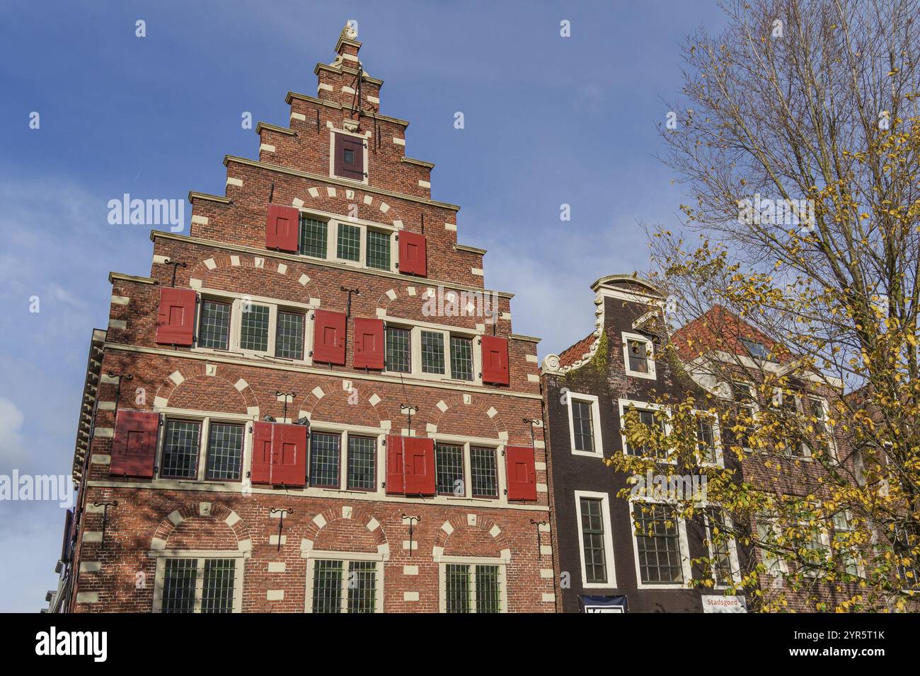 Brick building with stepped gable and red shutters under a blue sky ...