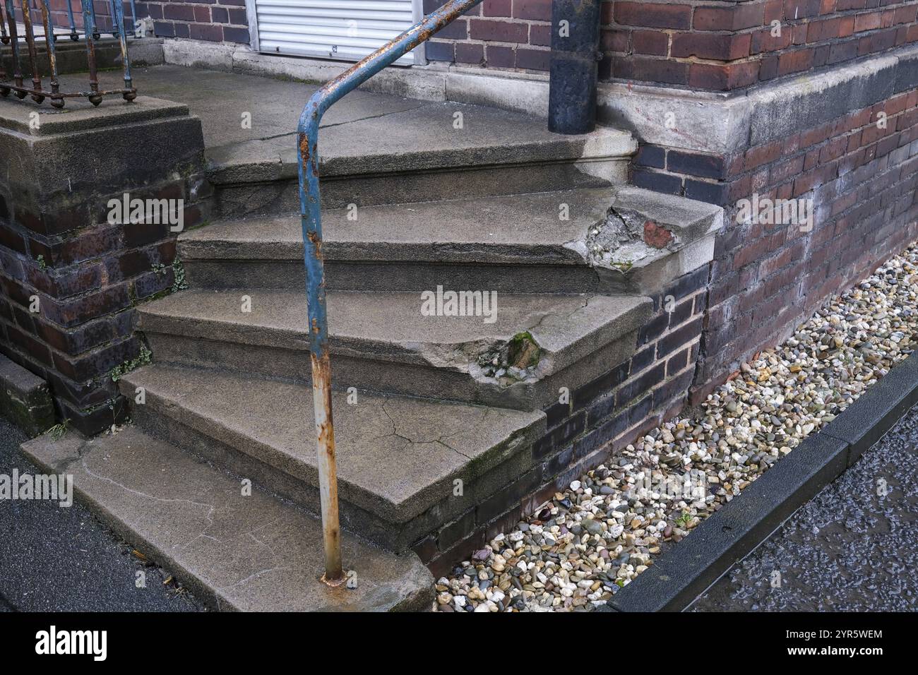 Concrete steps with a rusty handrail and visible wear, adjoining a ...