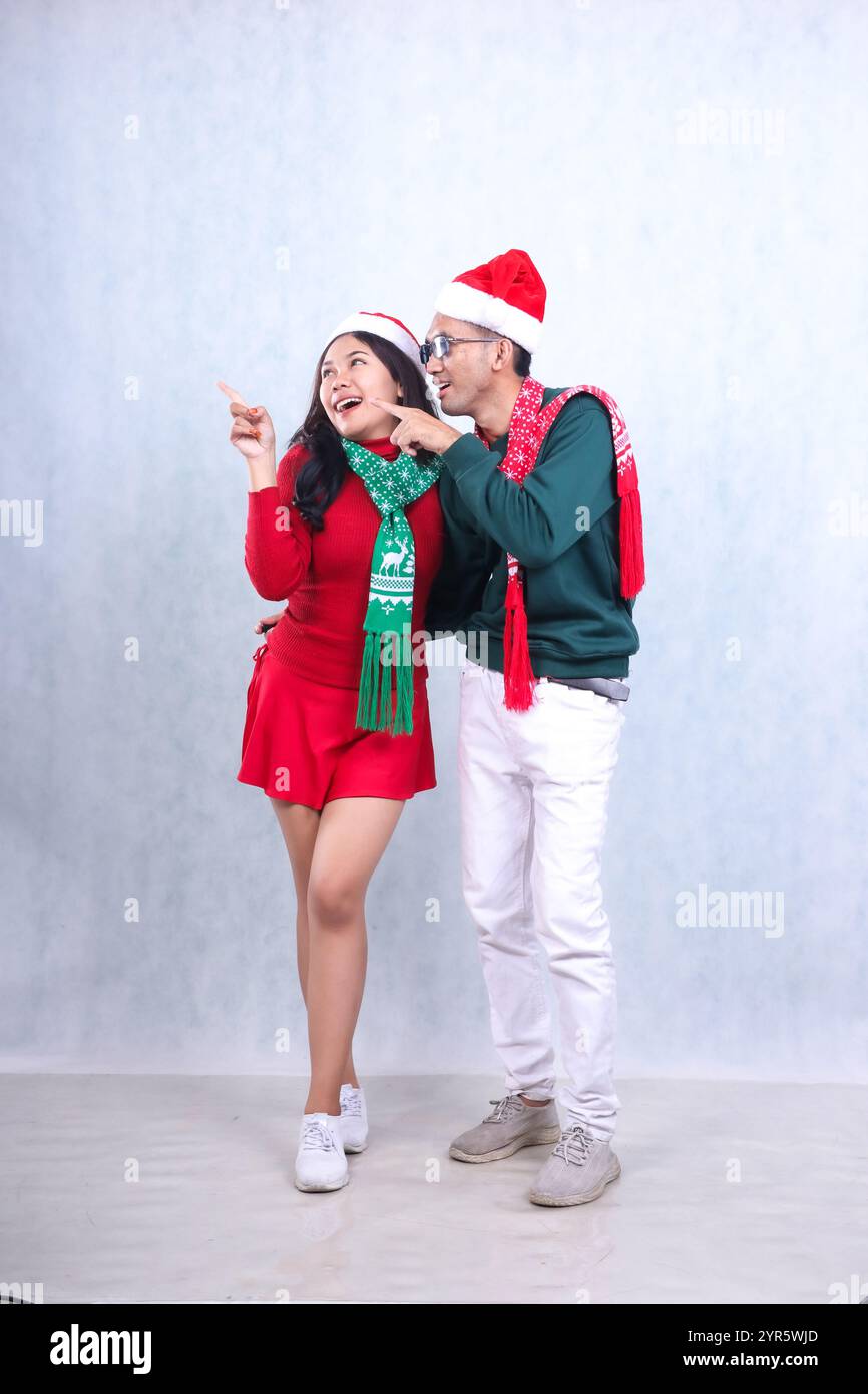 Full body Asian couple wearing party clothes with Santa hats ...