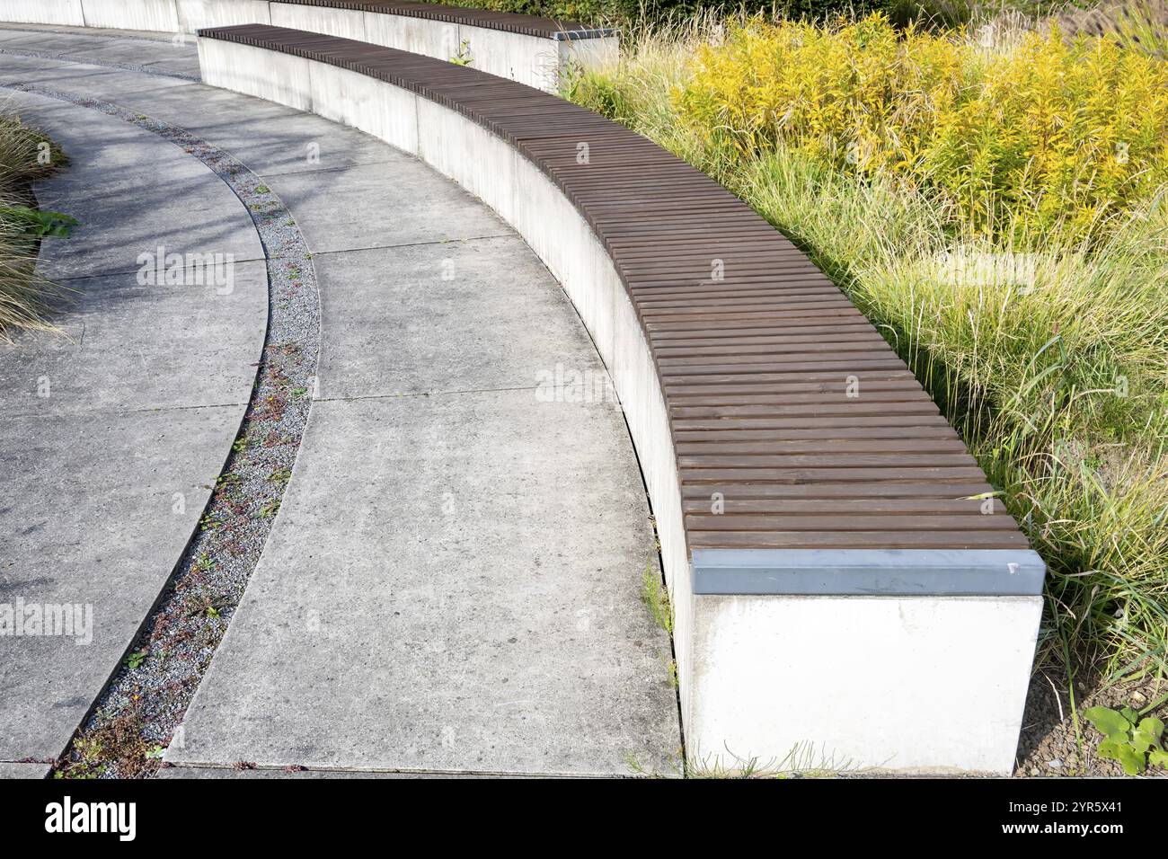 Modern curved bench in concrete with wooden support in park Stock Photo ...