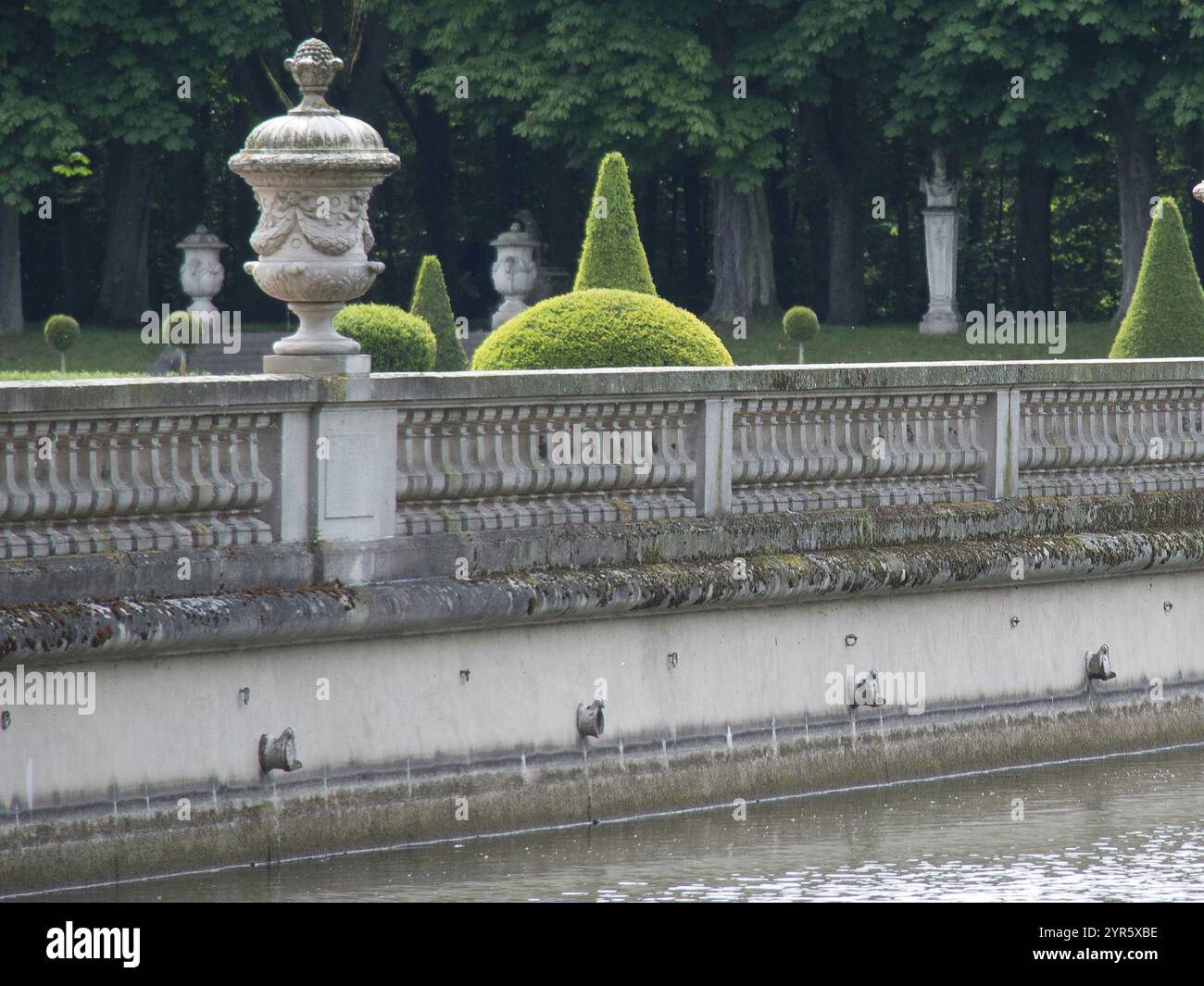 Elegant stone balustrade along a water, surrounded by classic garden ...