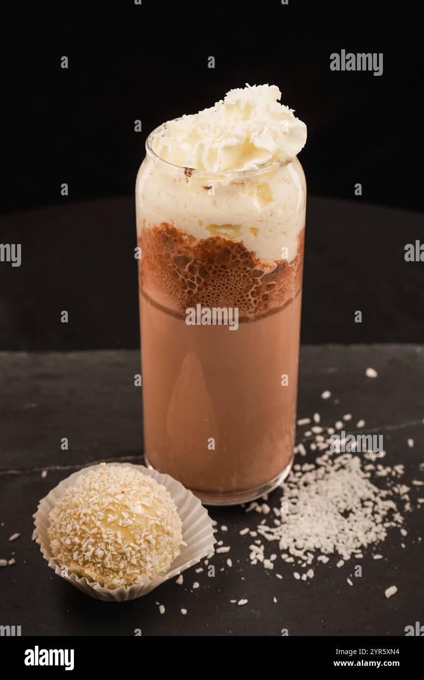 Chocolate milkshake with whipped cream served in a glass on a black ...