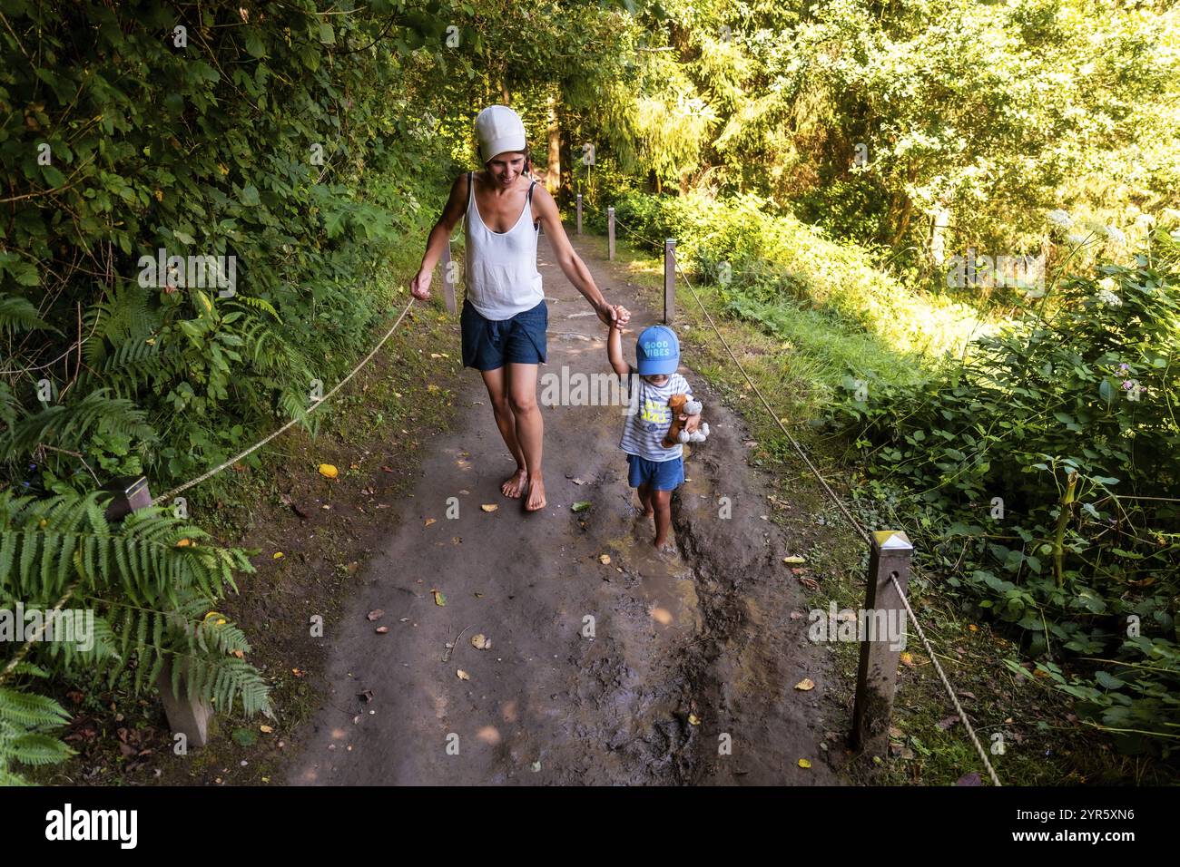 Walking happily barefoot through mud and water in a sensory park to ...