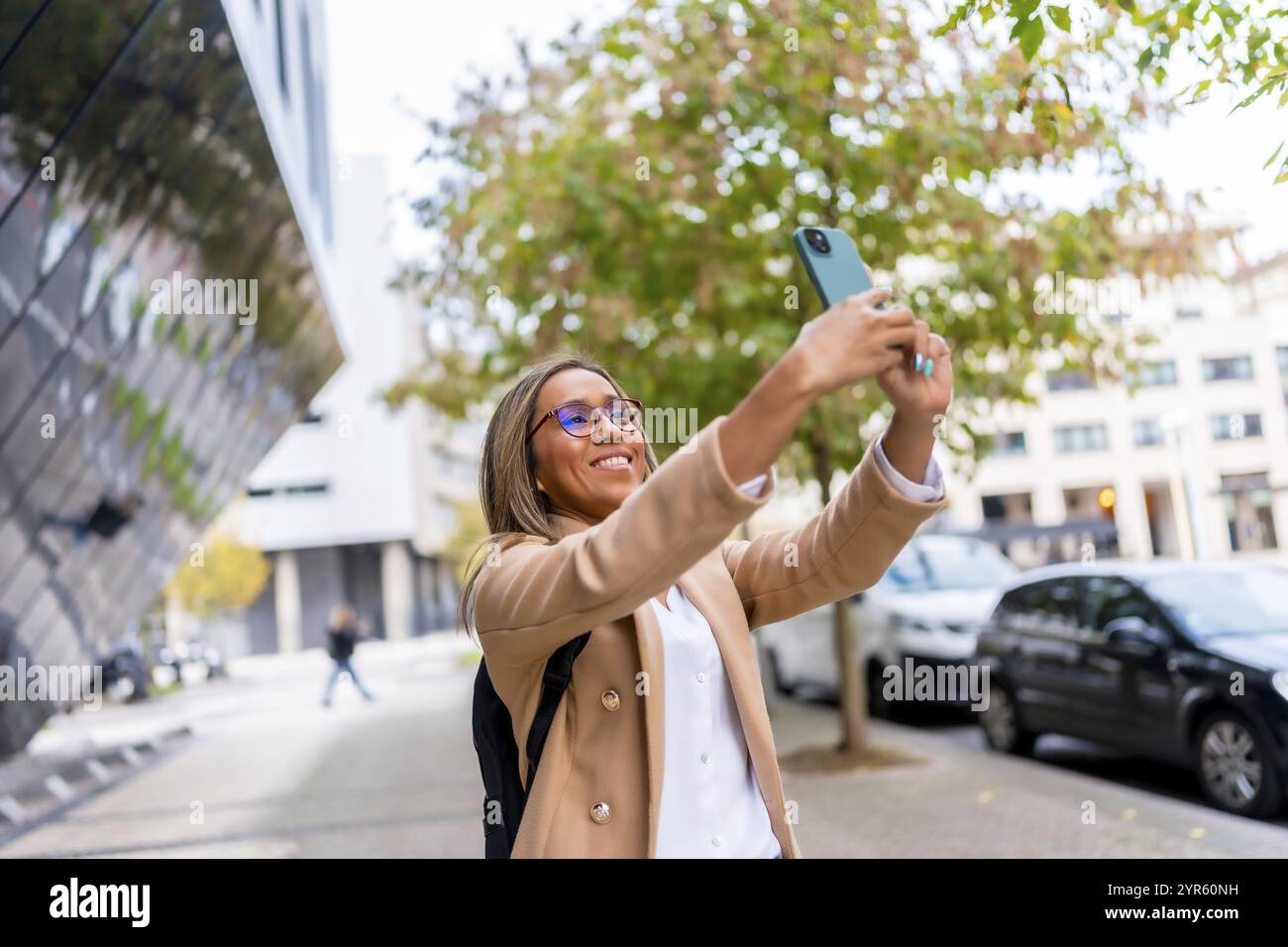 Latin woman in casual business clothes visiting a city taking photos ...