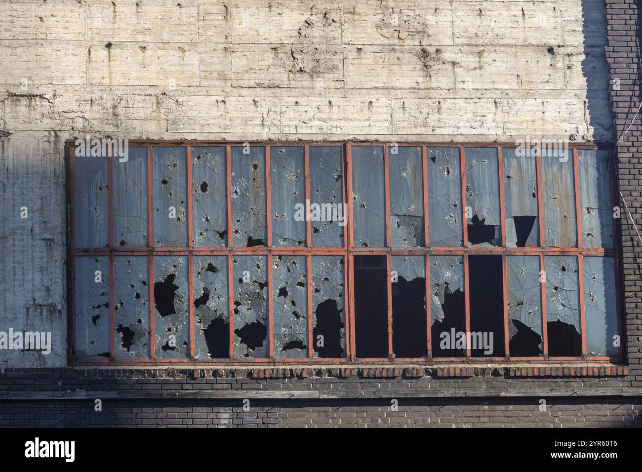 Old factory wall with broken and damaged windows, showing signs of ...