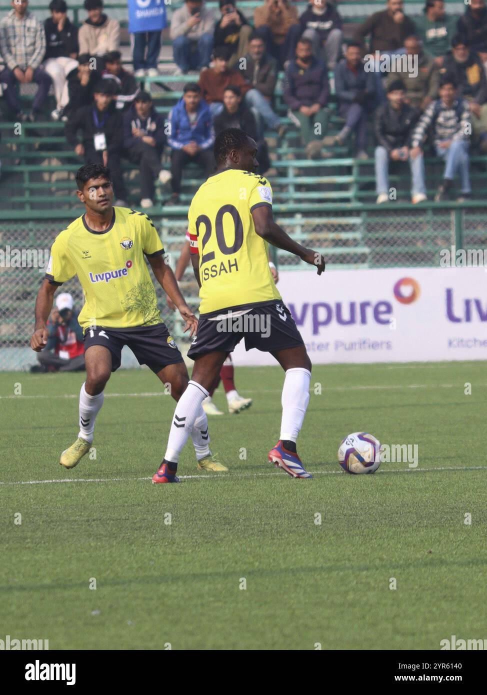 Two football players in yellow jerseys coordinating during a match on ...