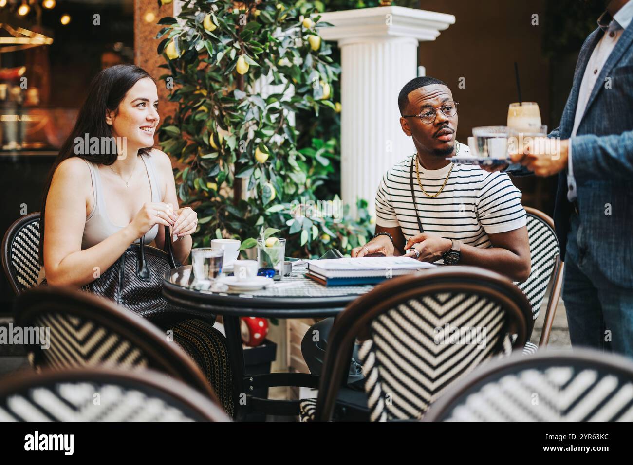 Friends enjoying coffee at an outdoor cafe table setting Stock Photo ...