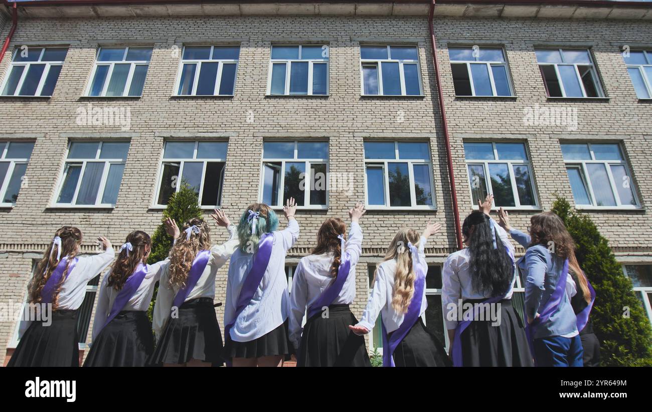 Graduating students waving goodbye to their school as they celebrate ...
