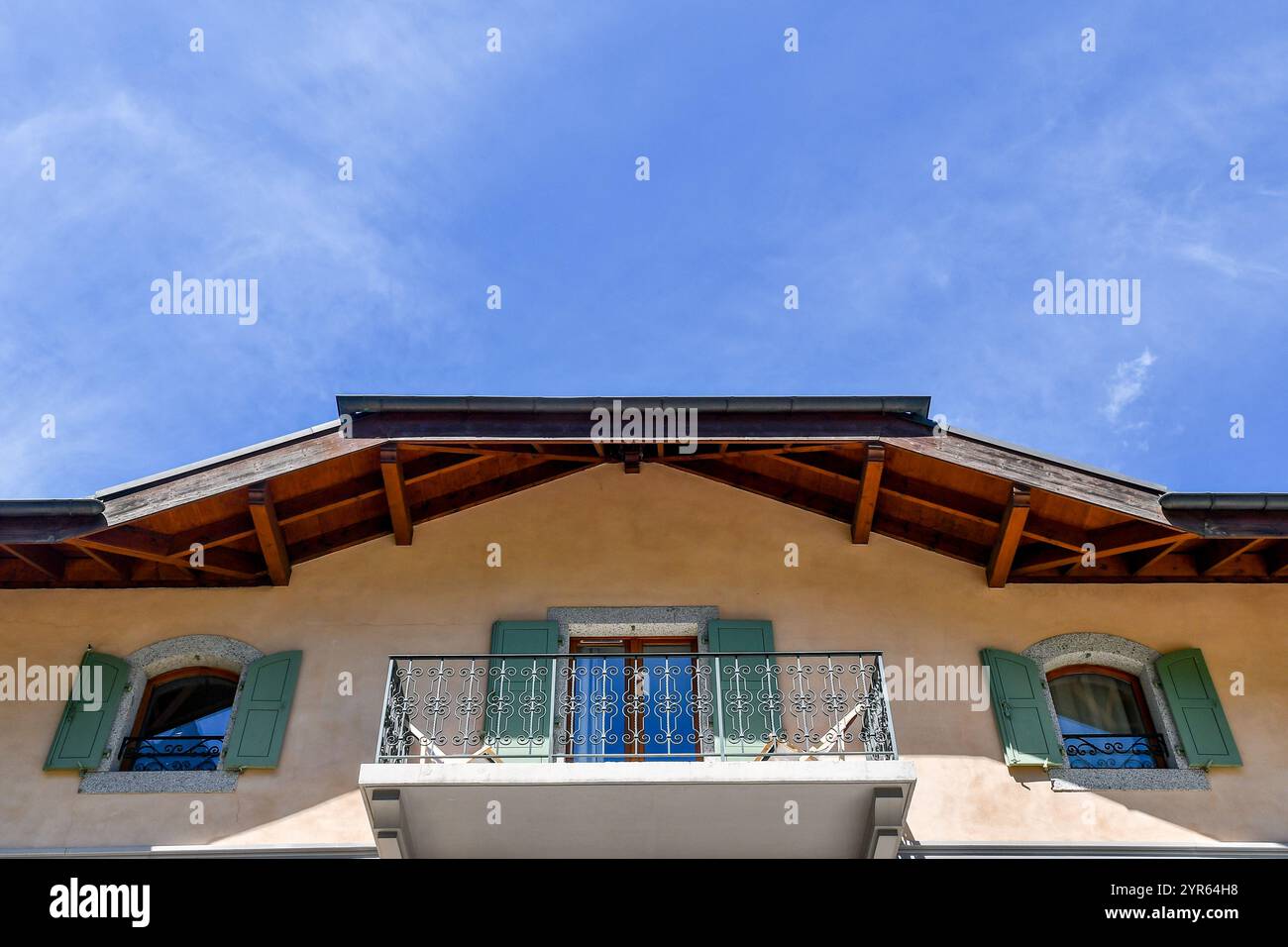 Low-angle view of the attic of a mountain house with a balcony and pale ...