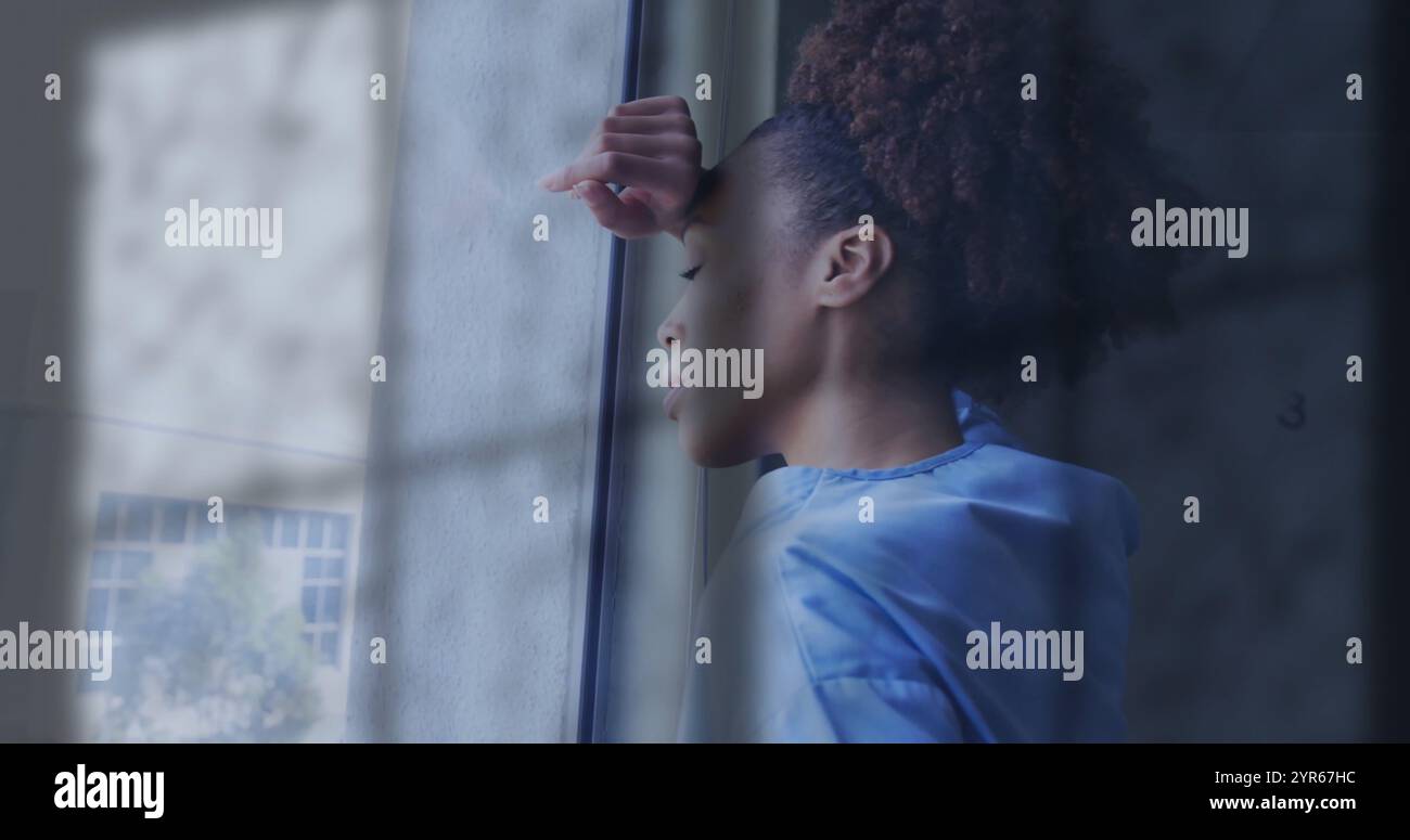 Image of rain on window over unhappy african american female doctor ...