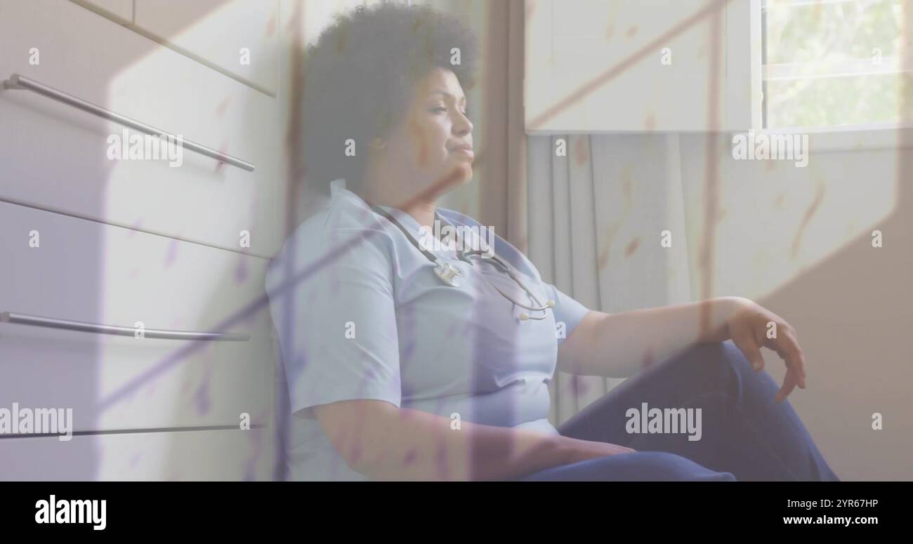 Image of rain on window over unhappy african american female doctor ...