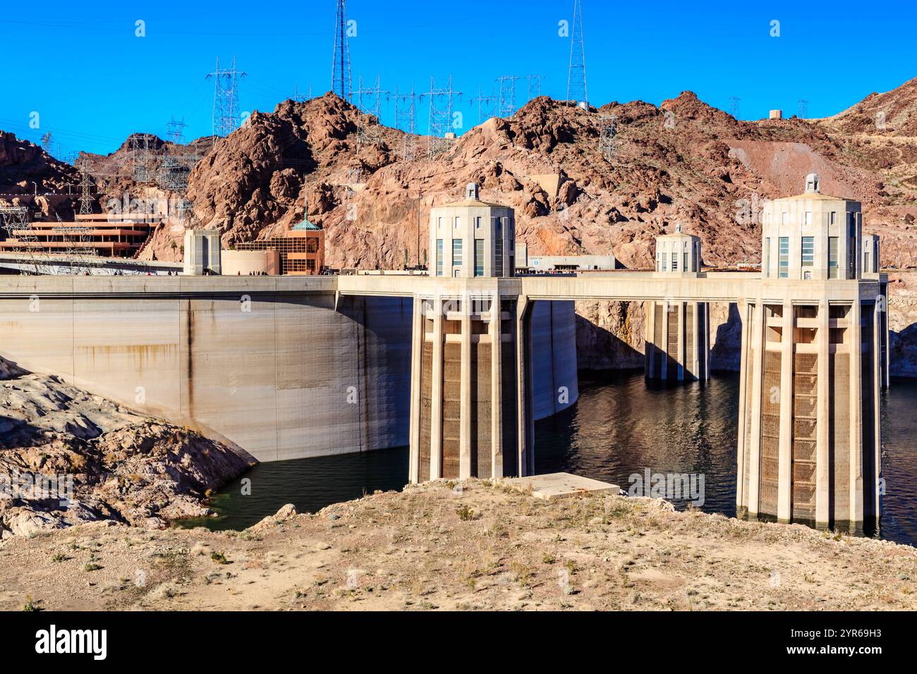 A large dam is seen in the distance with a body of water in front of it ...
