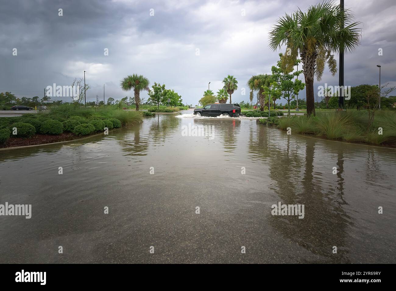 vehicle driving in parking lot submerged under heavy rain, with water ...
