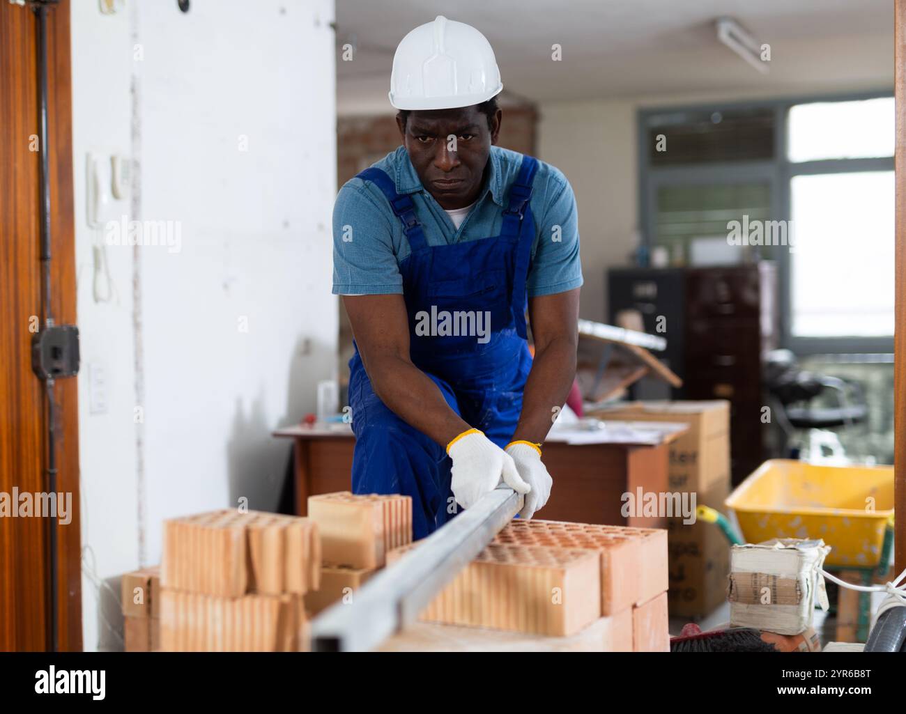 African american builder arranging metal tubes in building under ...