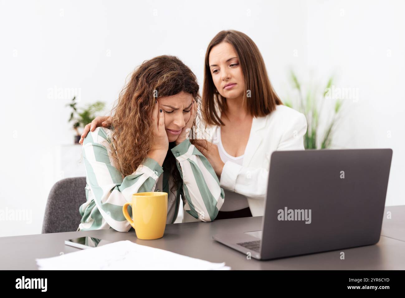 Coworker comforts distressed colleague in the office Stock Photo - Alamy