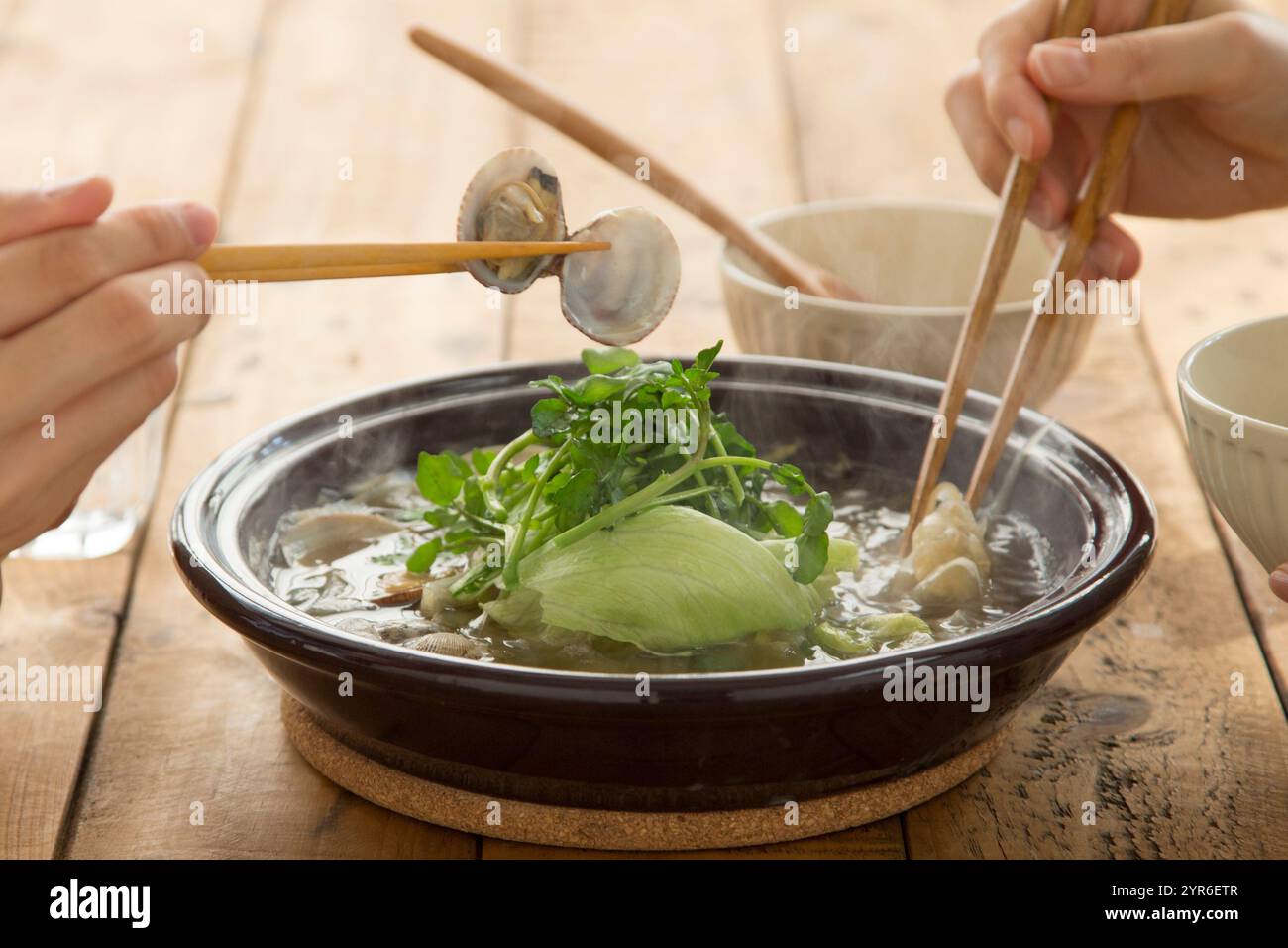 Eating Japanese-style one-pot dish of asari clam and Japanese parsley ...