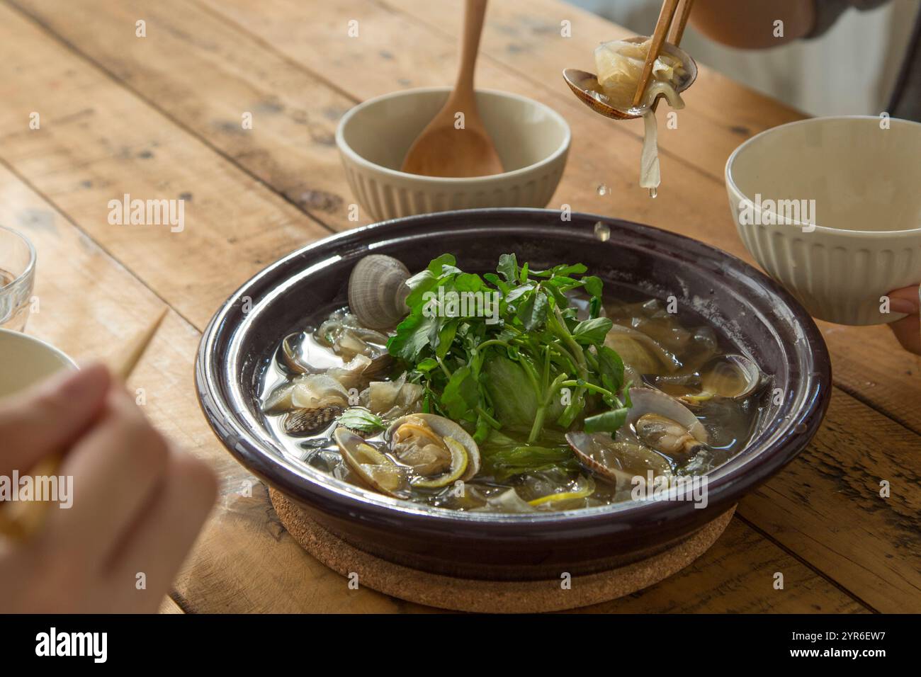 Eating Japanese-style one-pot dish of asari clam and Japanese parsley ...