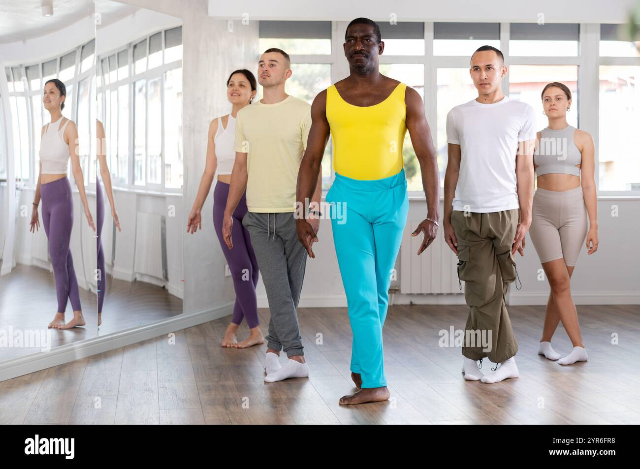 Multinational group of young people stand in row holding hands ...